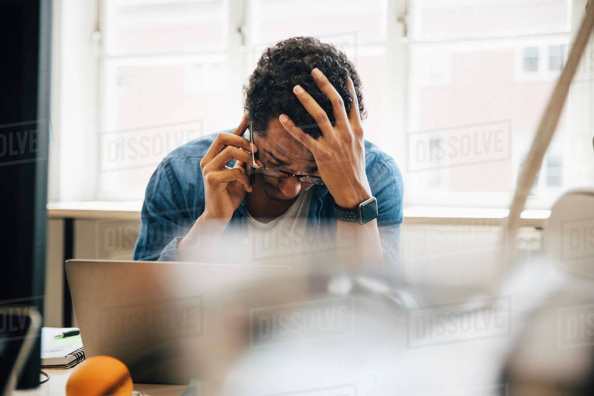 Frustrated male computer hacker with hand in hair talking on smart ...