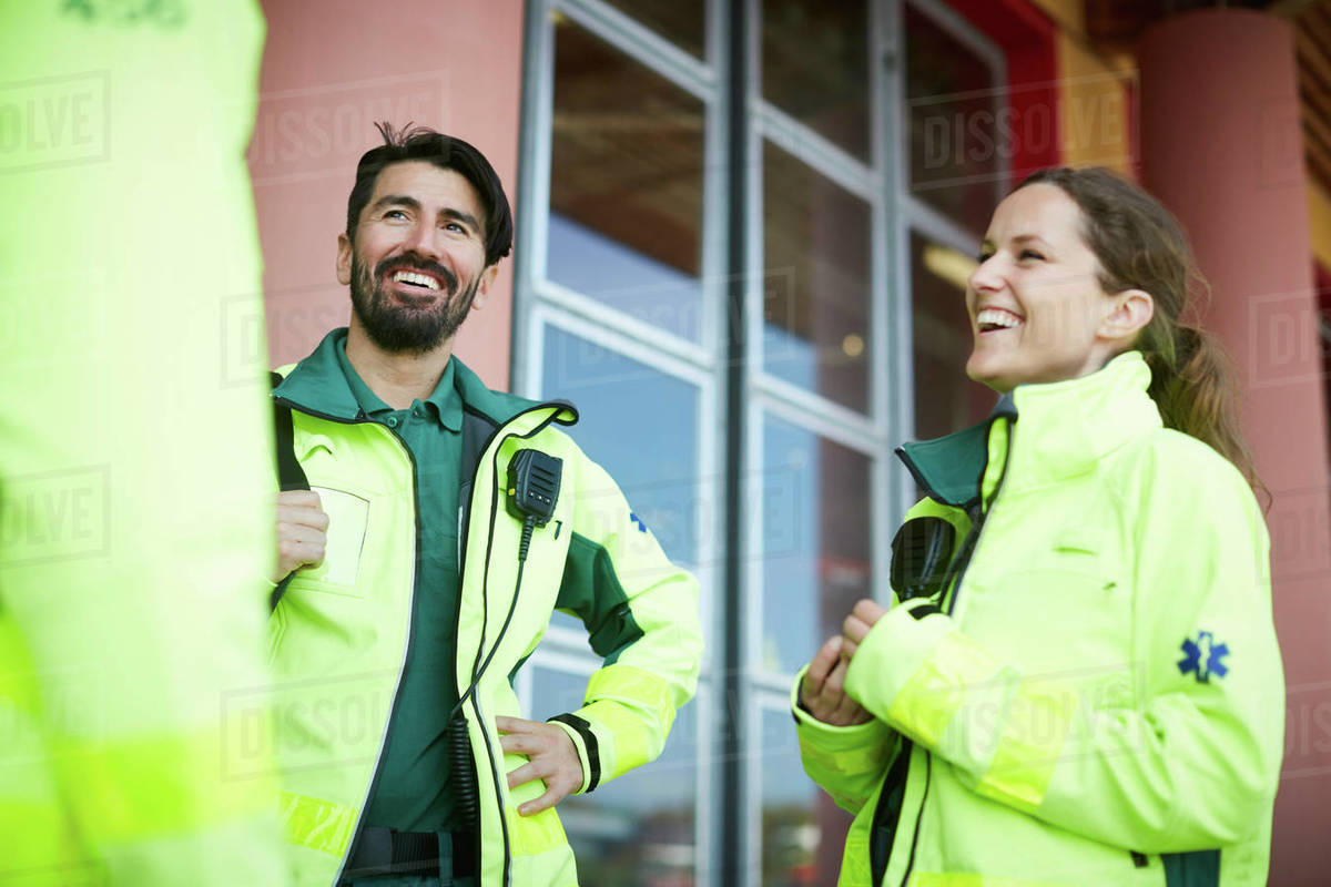 Smiling paramedics talking while standing outside hospital - Royalty ...