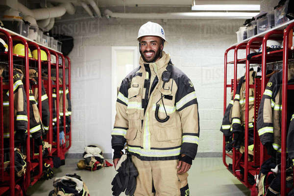 Portrait of smiling male firefighter in locker room at fire station ...