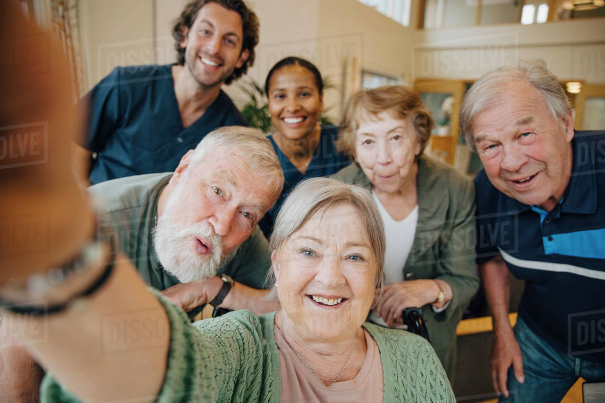 Retired elderly woman taking selfie with friends and caregivers at ...