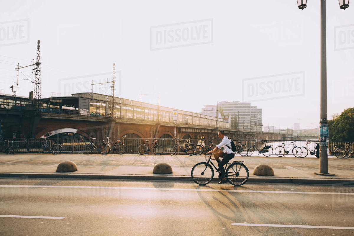 Side view of male executive riding bicycle on street in city against ...