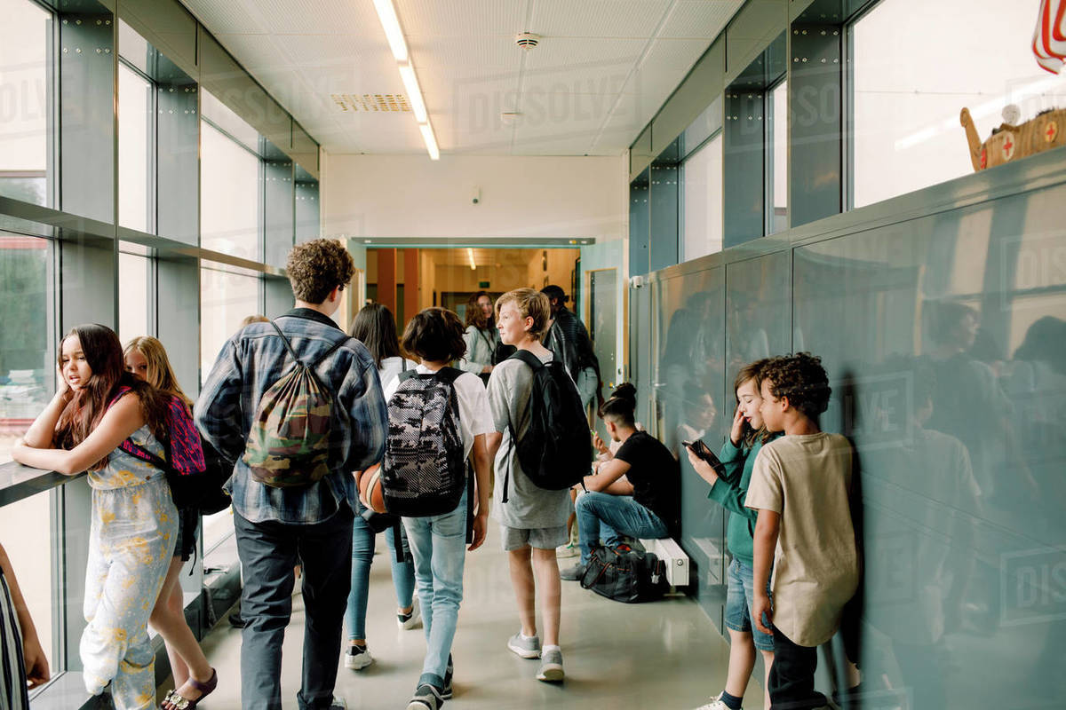 Rear view of students walking in school corridor - Royalty-free Stock ...