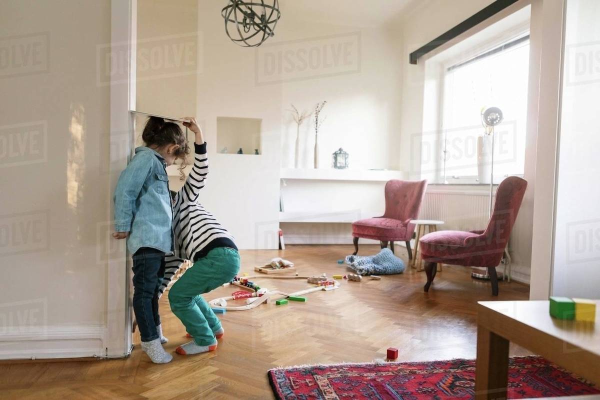 Low section of brother measuring sister's height on wall with book at ...