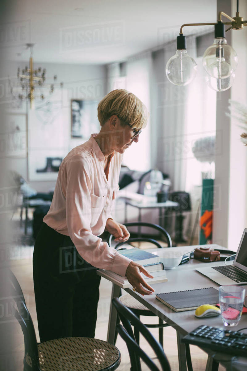 Woman standing at table working at home - Royalty-free Stock Photo ...