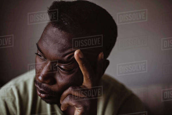 Close-up of sad man holding head in hand while looking away - Stock ...