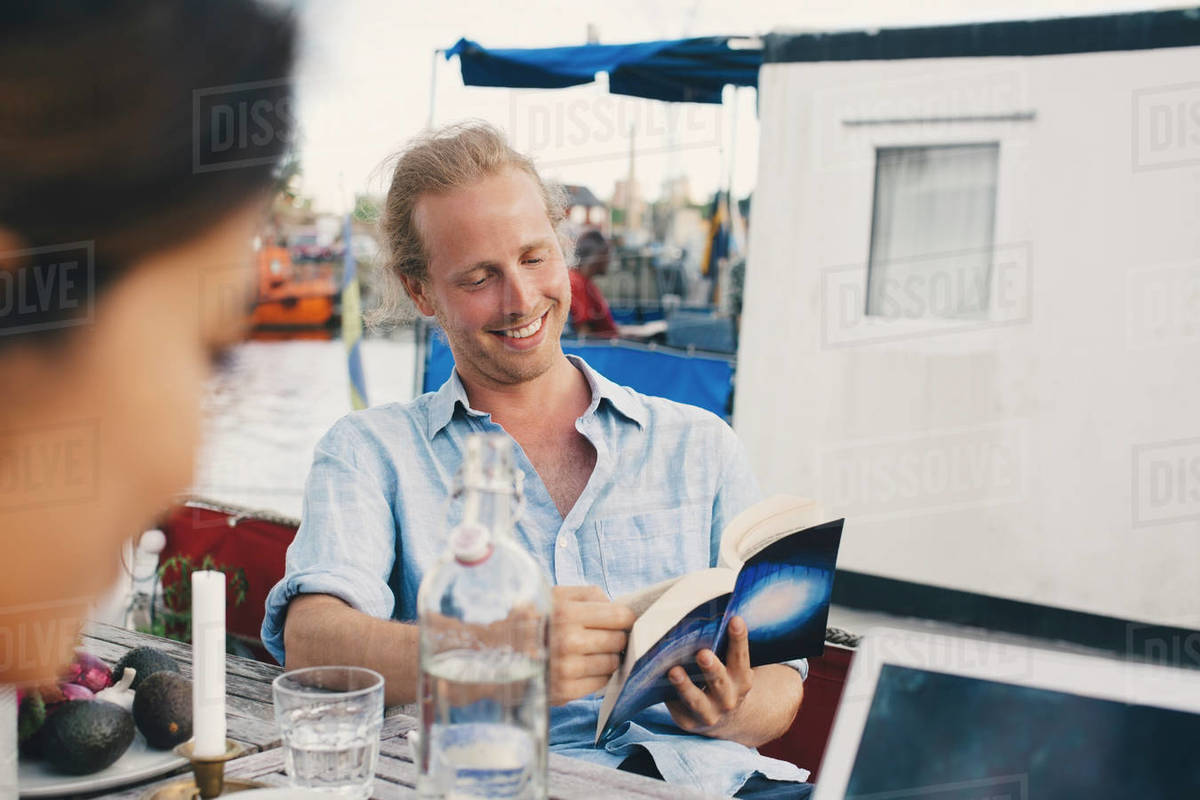 Man smiling while reading book at houseboat - Royalty-free Stock Photo ...