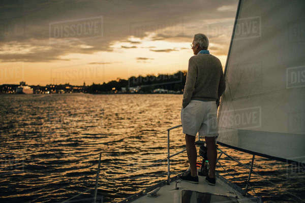 Rear view of senior man looking at sea during sunset - Royalty-free ...