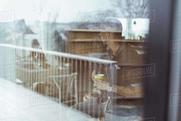 Hispanic man seen through glass window - Stock Photo - Dissolve