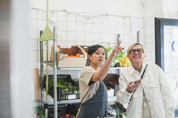 Female owner pointing while talking with female customer in store ...