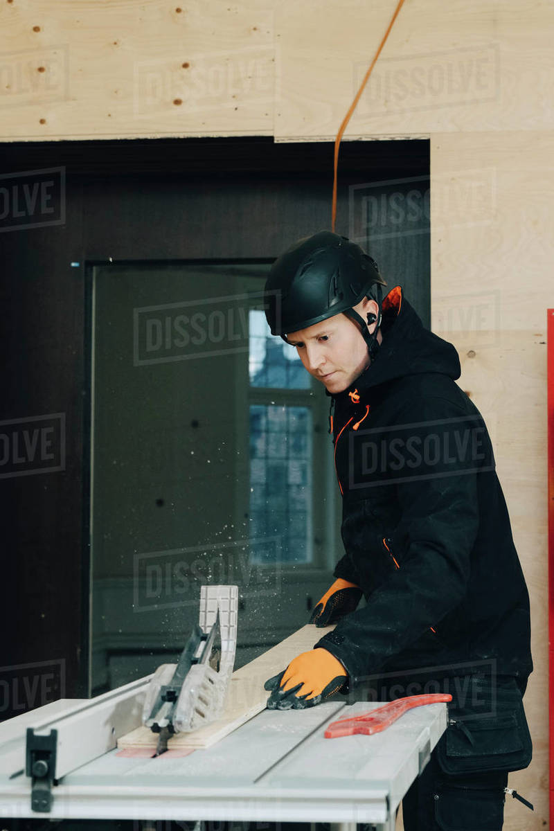 Male worker using table saw for cutting wooden plank while working at ...