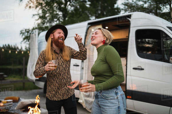Happy young couple dancing by camping van in evening - Royalty-free ...