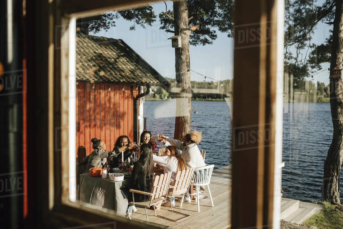 Female friends celebrating during party seen through window - Stock ...
