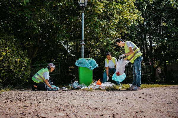 Male and female activists picking up plastic waste in park - Royalty ...