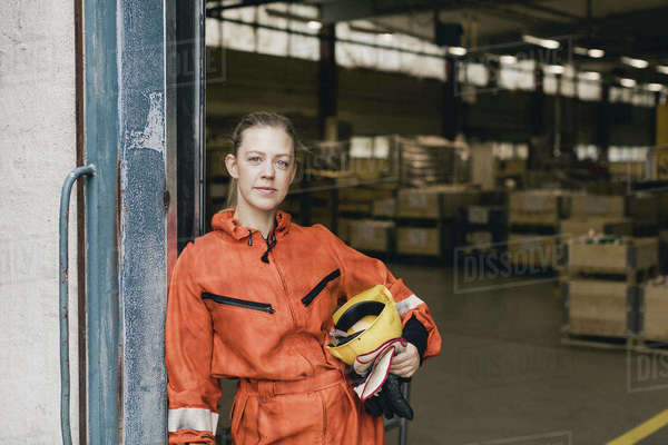 Portrait of female blue-collar worker in uniform standing at factory ...