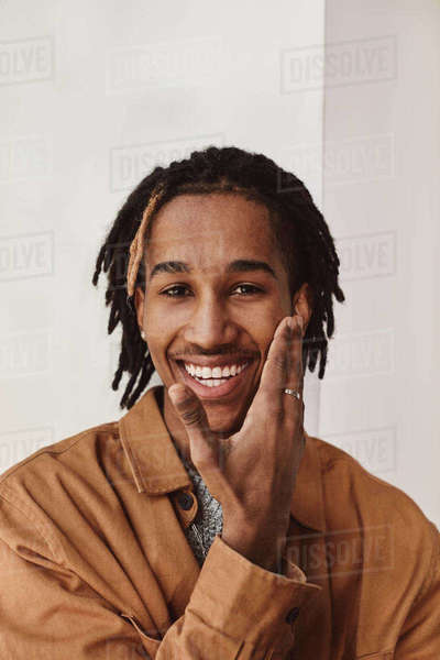 Portrait of smiling man touching cheek against white background ...