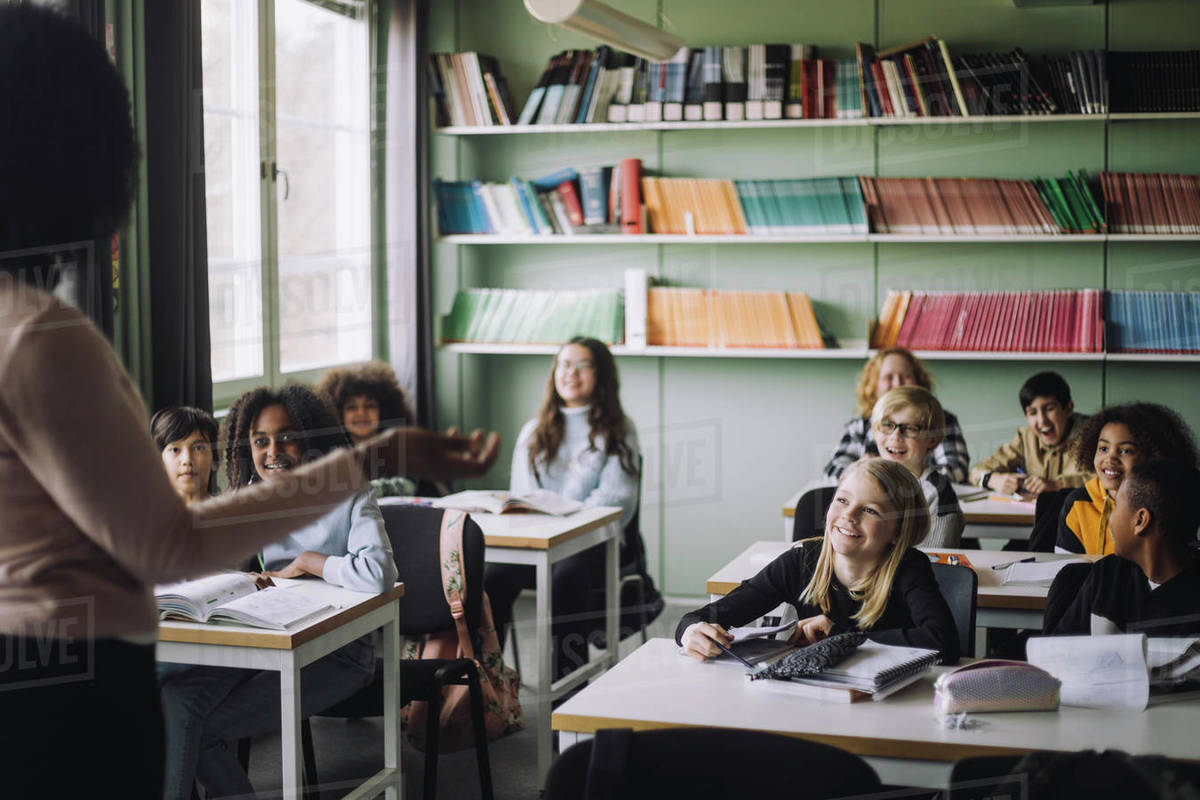 Happy students looking at teacher teaching in classroom - Royalty-free ...