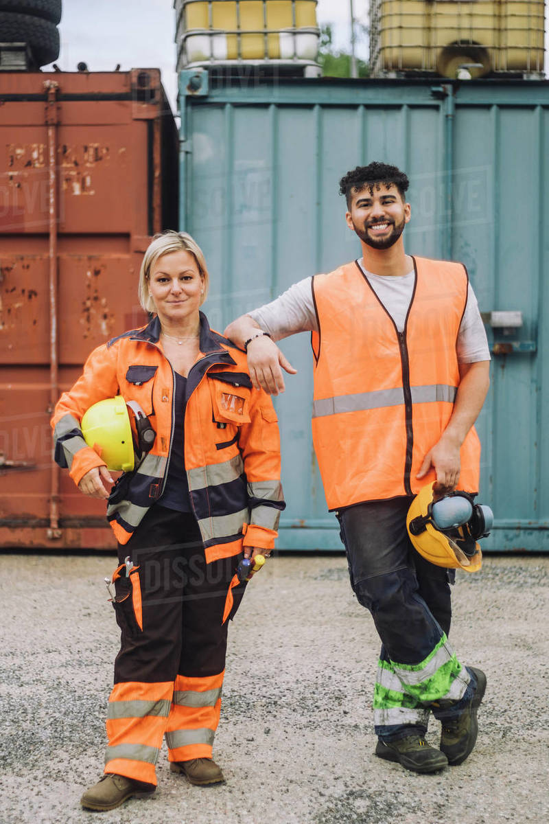 Full length of smile male and female construction workers in reflective ...