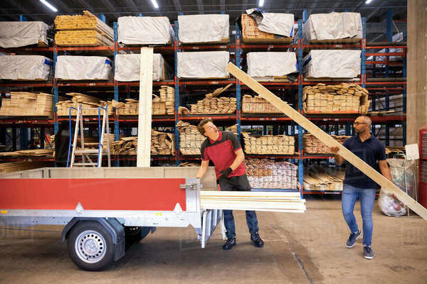 Male customer loading wooden plank in trailer at hardware store - Stock ...