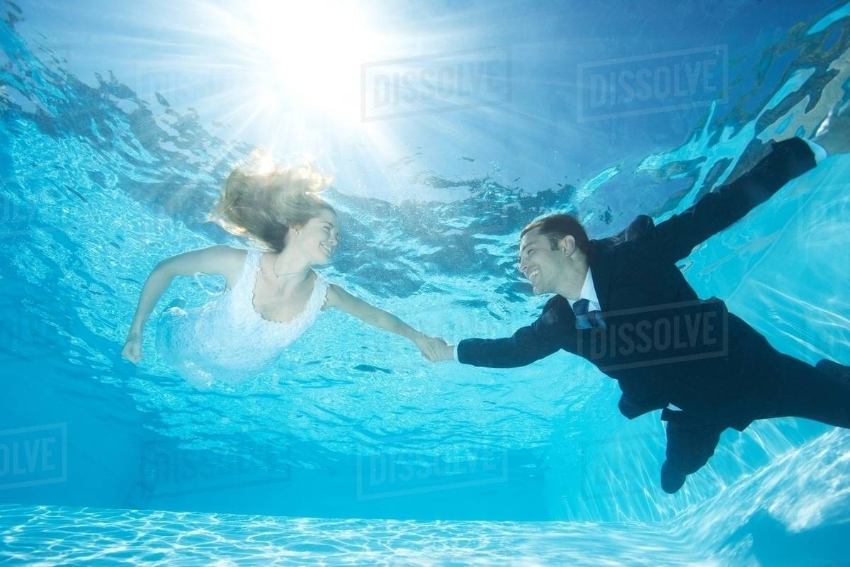 Bride and groom together in pool - Stock Photo - Dissolve