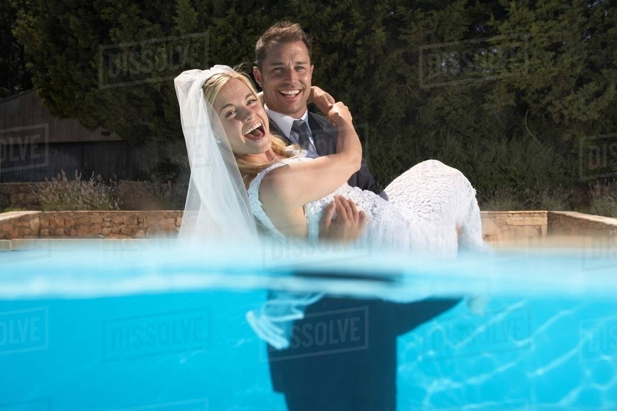 Groom carrying bride in pool - Royalty-free Stock Photo | Dissolve