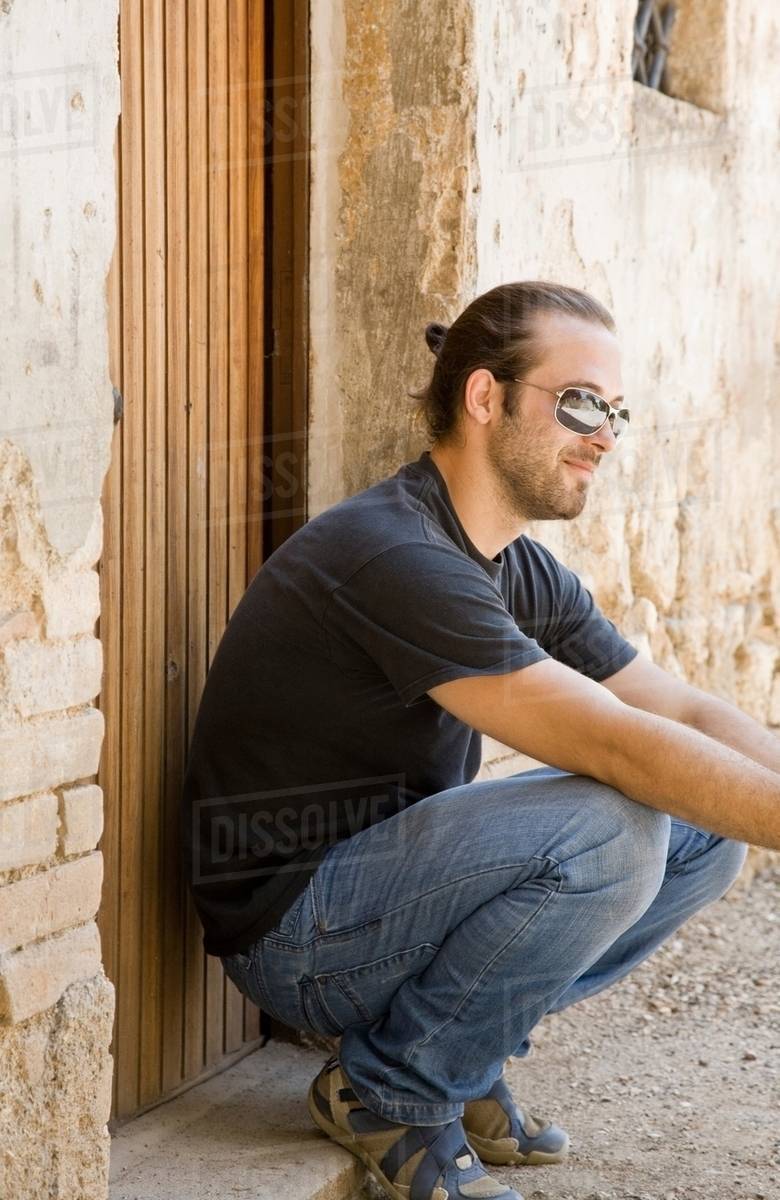 Man crouch down by a doorway - Royalty-free Stock Photo | Dissolve