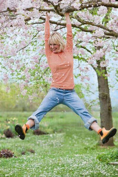 Woman hanging from tree branch - Stock Photo - Dissolve