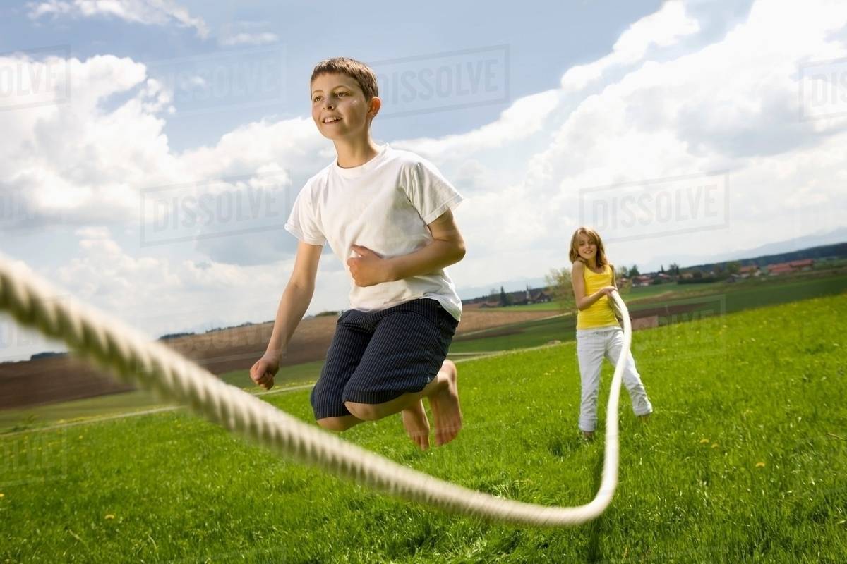 Children jump roping in countryside - Royalty-free Stock Photo | Dissolve