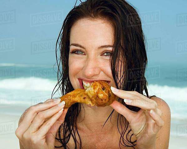 Young women eating a chicken leg - Stock Photo - Dissolve