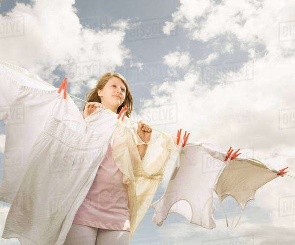 Girl putting clothing on a washing line - Stock Photo - Dissolve