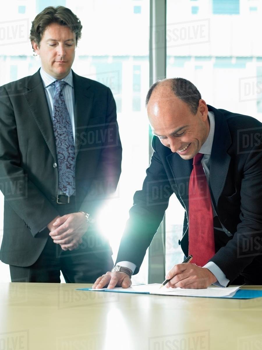 Business man signing papers with partner - Stock Photo - Dissolve