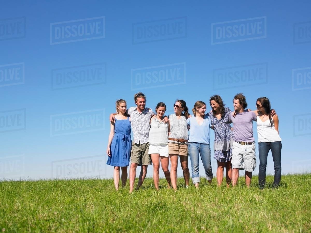 Group of young people walking in field - Stock Photo - Dissolve