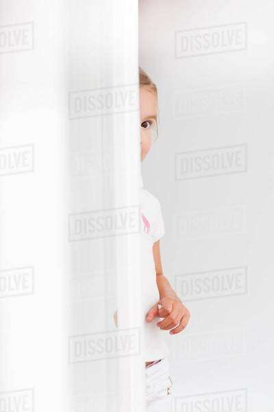Young girl looking around corner - Stock Photo - Dissolve