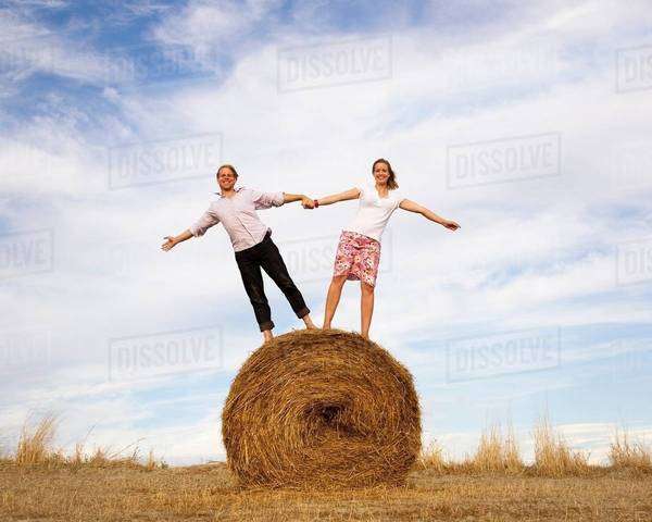 Woman and man standing on hay bale - Royalty-free Stock Photo | Dissolve