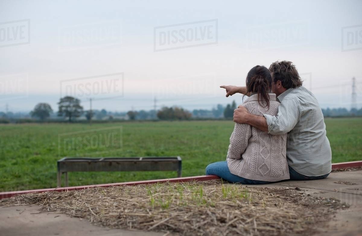 Couple watching sunrise over fields - Royalty-free Stock Photo | Dissolve