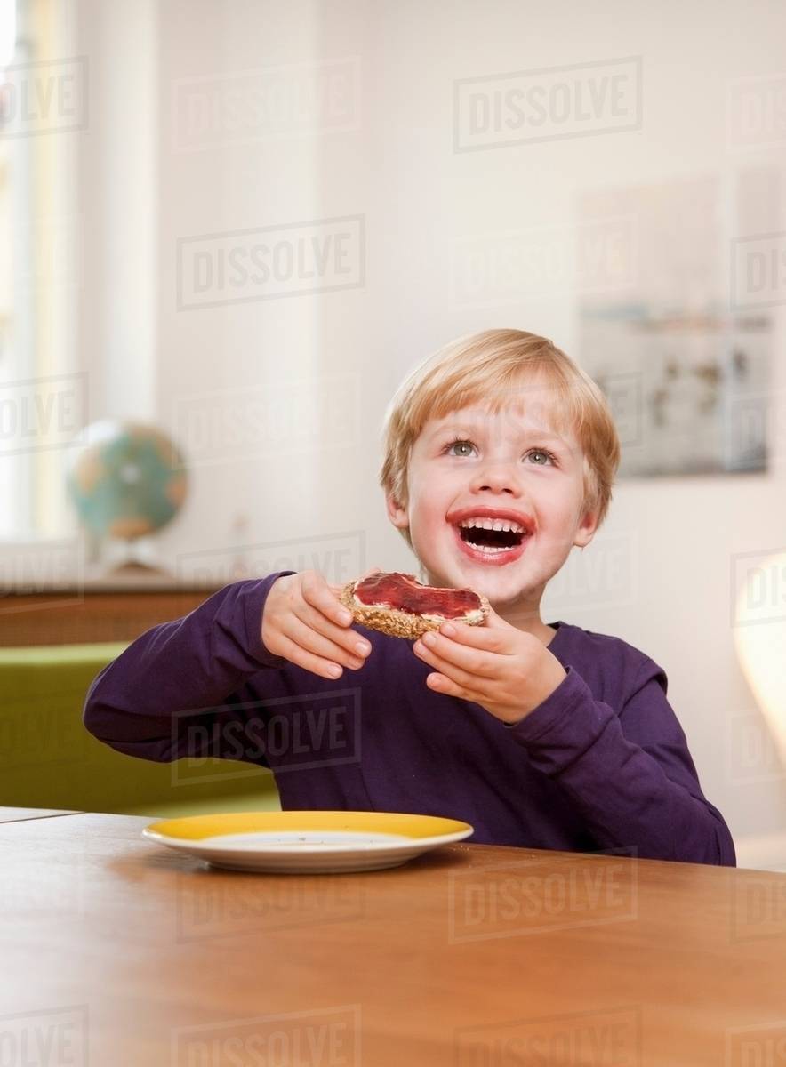 Boy eating bread roll - Stock Photo - Dissolve