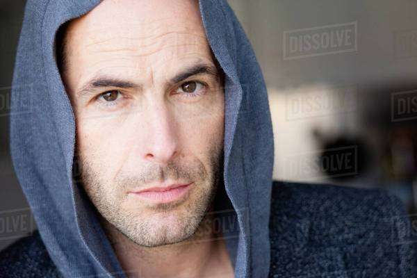Man with hood looking at viewer - Stock Photo - Dissolve