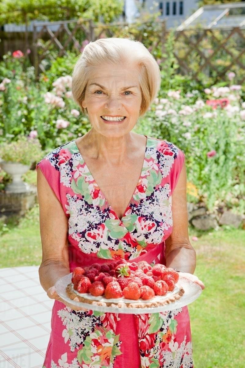 Mature woman holding strawberry tart. - Stock Photo - Dissolve