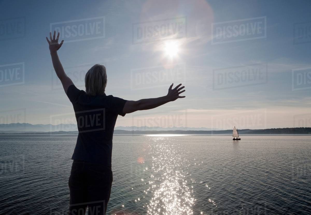 Man watching the sun set over a lake - Royalty-free Stock Photo | Dissolve