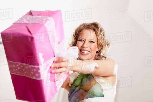Woman handing over present - Royalty-free Stock Photo | Dissolve