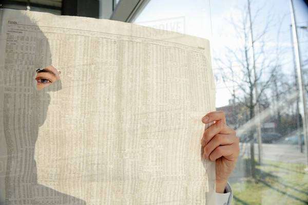 Man spying through hole in newspaper - Stock Photo - Dissolve