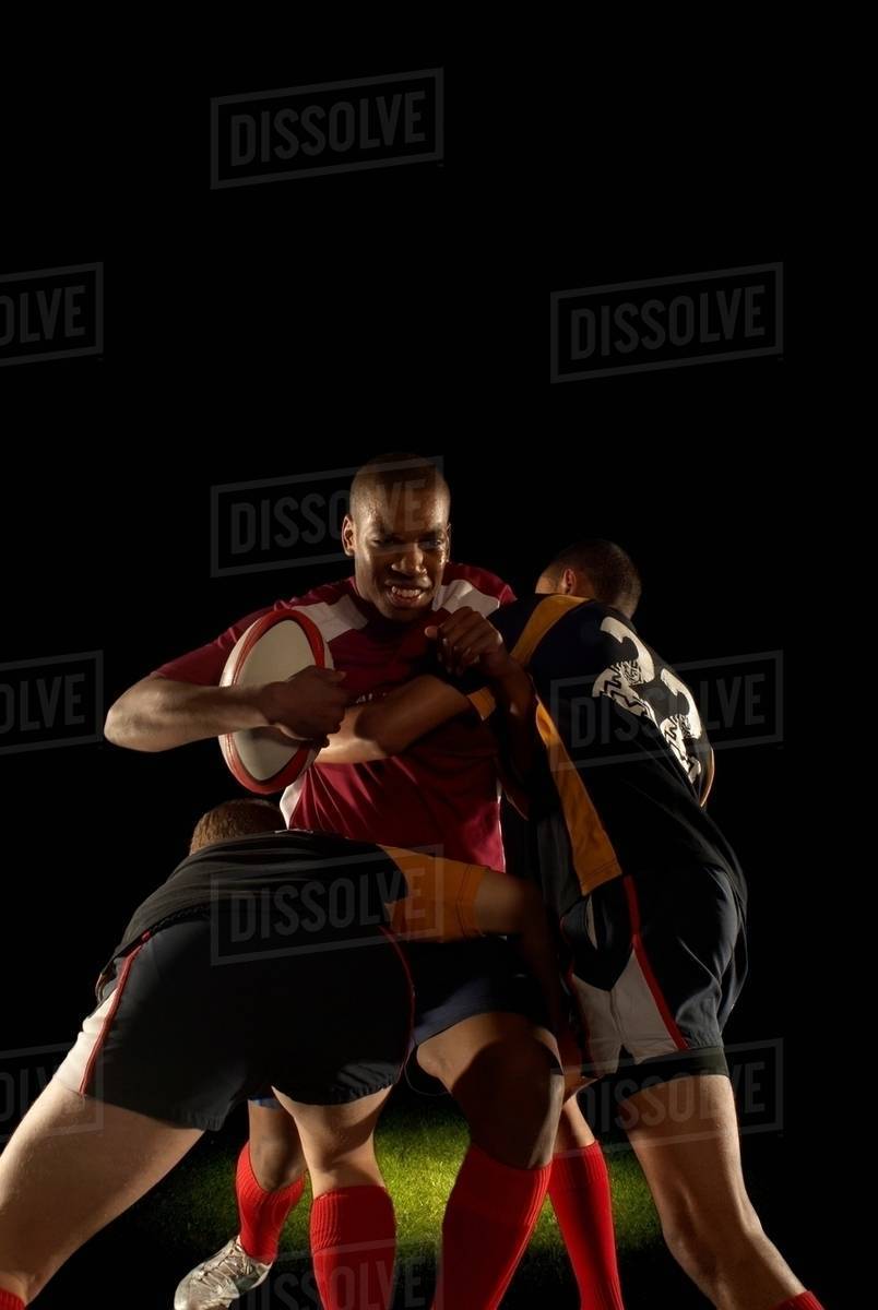 Two rugby players tackling one opponent - Stock Photo - Dissolve