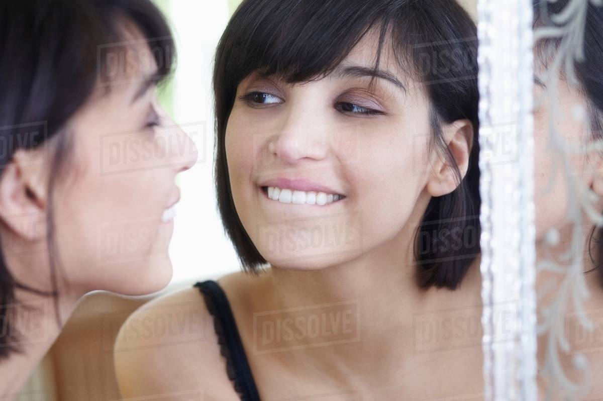 Woman looking in the mirror - Stock Photo - Dissolve