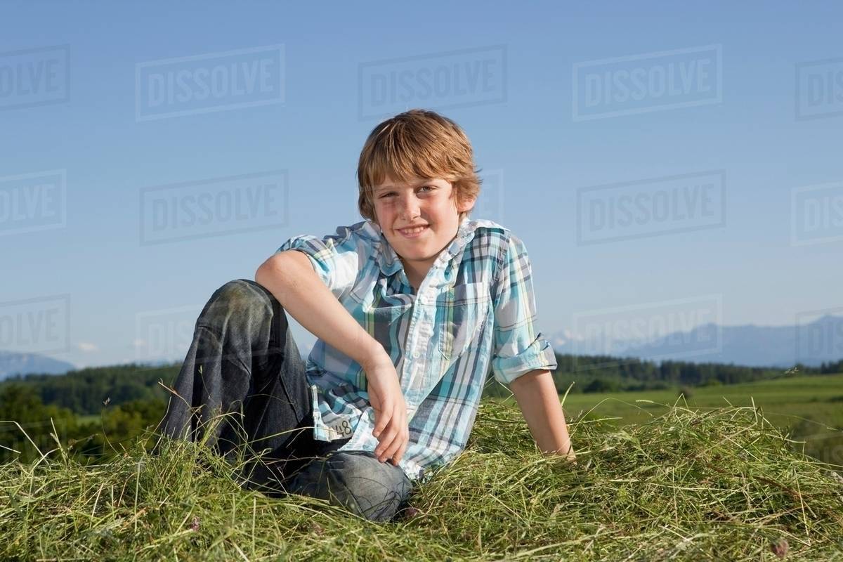 Boy sitting in grass - Stock Photo - Dissolve