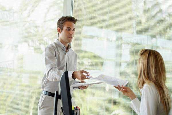 Office worker handing document to woman - Stock Photo - Dissolve