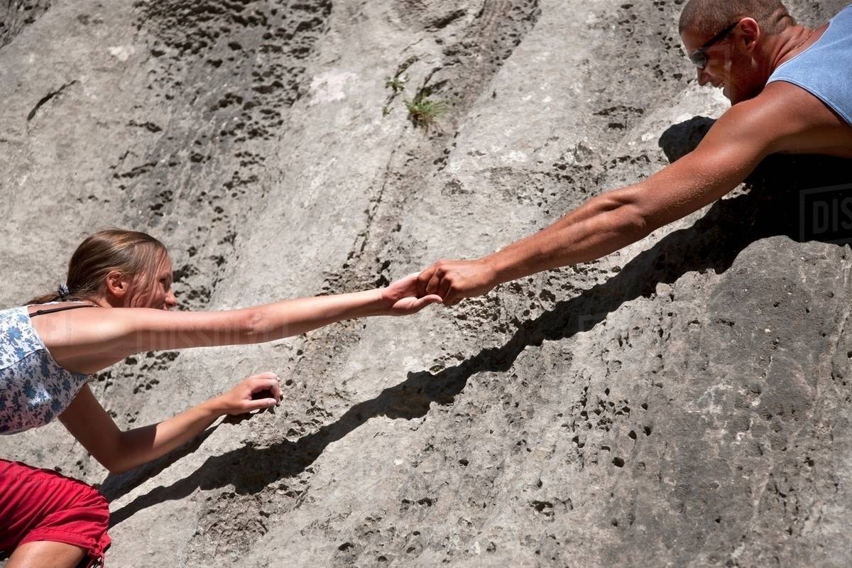 Rock climber helping partner - Stock Photo - Dissolve
