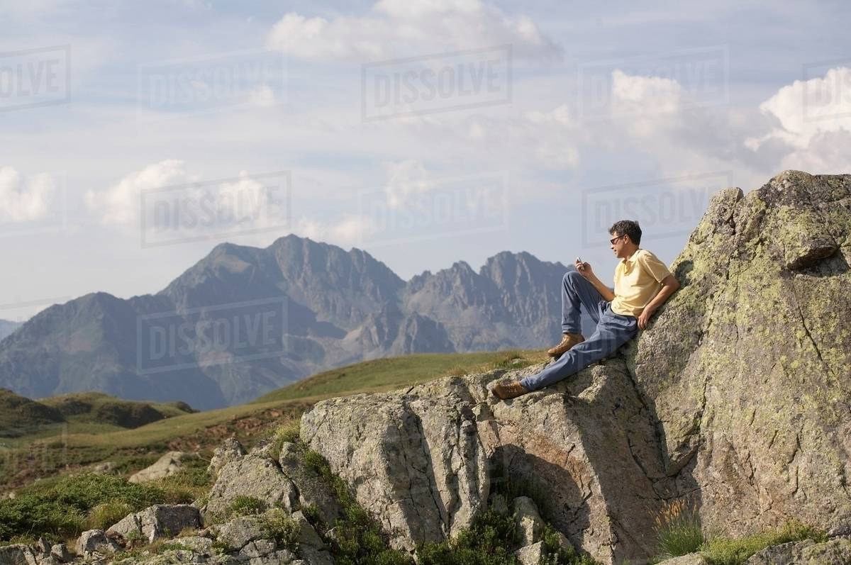 Man on phone looking over mountains - Royalty-free Stock Photo | Dissolve