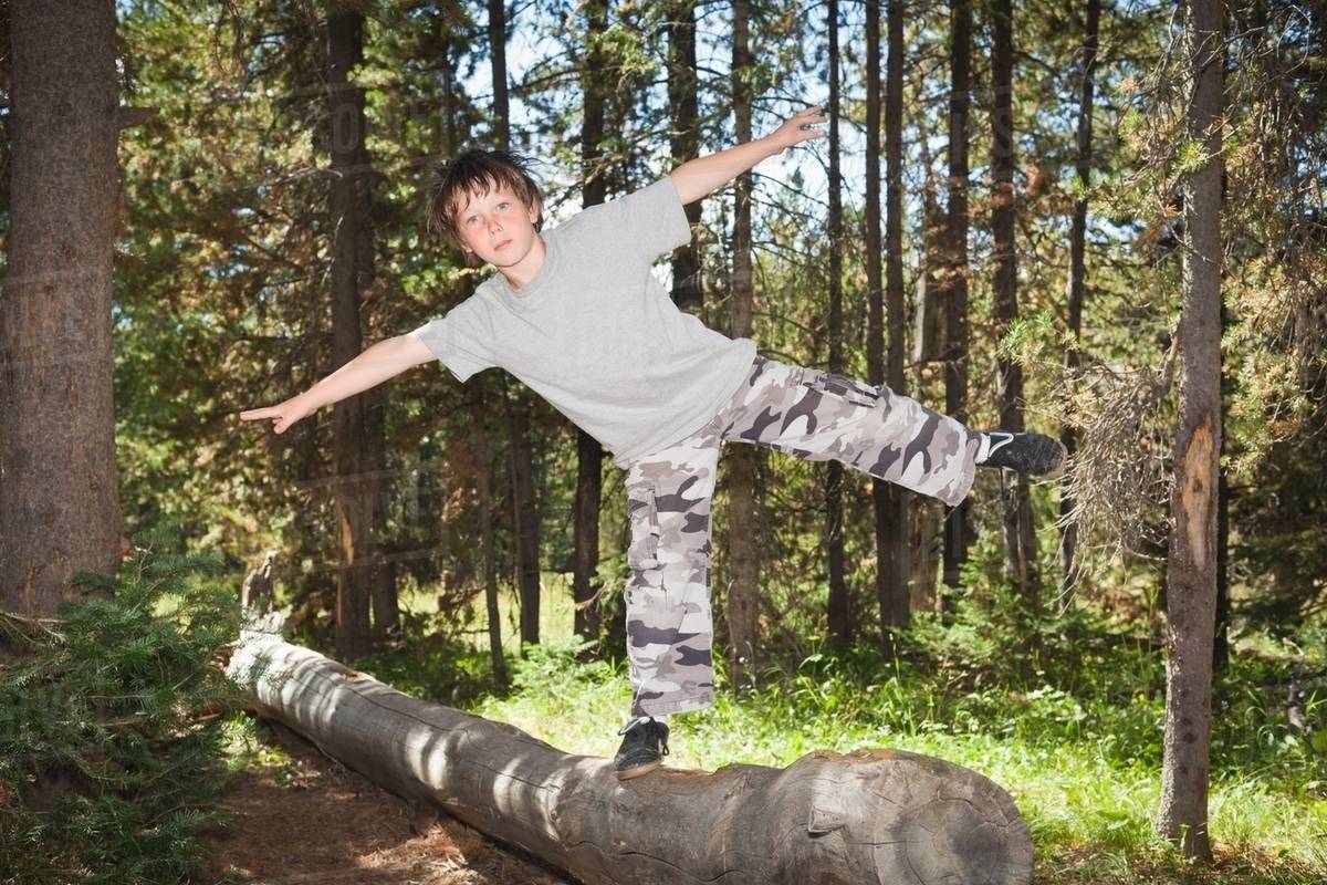 Boy balancing on log - Stock Photo - Dissolve