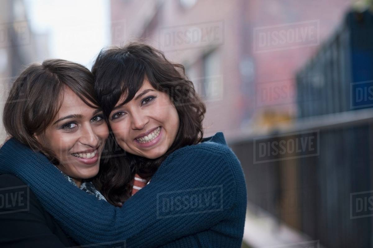 2 females hugging and posing to camera - Stock Photo - Dissolve