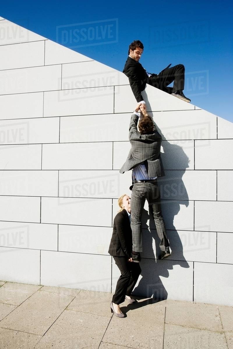 2 people helping man over wall - Royalty-free Stock Photo | Dissolve