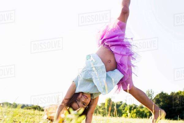 Cute girl wearing tutu cartwheeling in park - Stock Photo - Dissolve